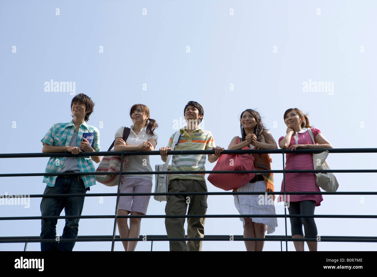 Five young people leaning on railing Stock Photo - Alamy