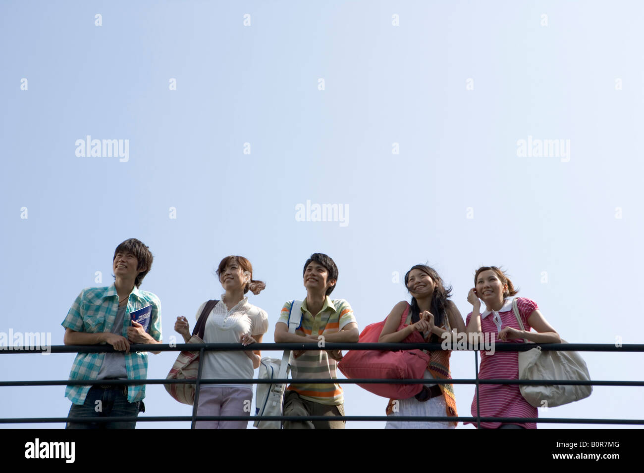 Five young people leaning on railing Stock Photo - Alamy