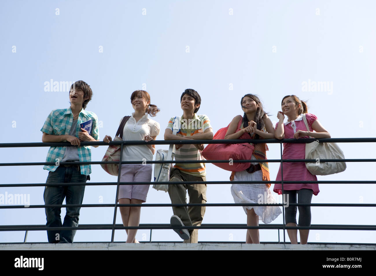 Five young people leaning on railing Stock Photo - Alamy