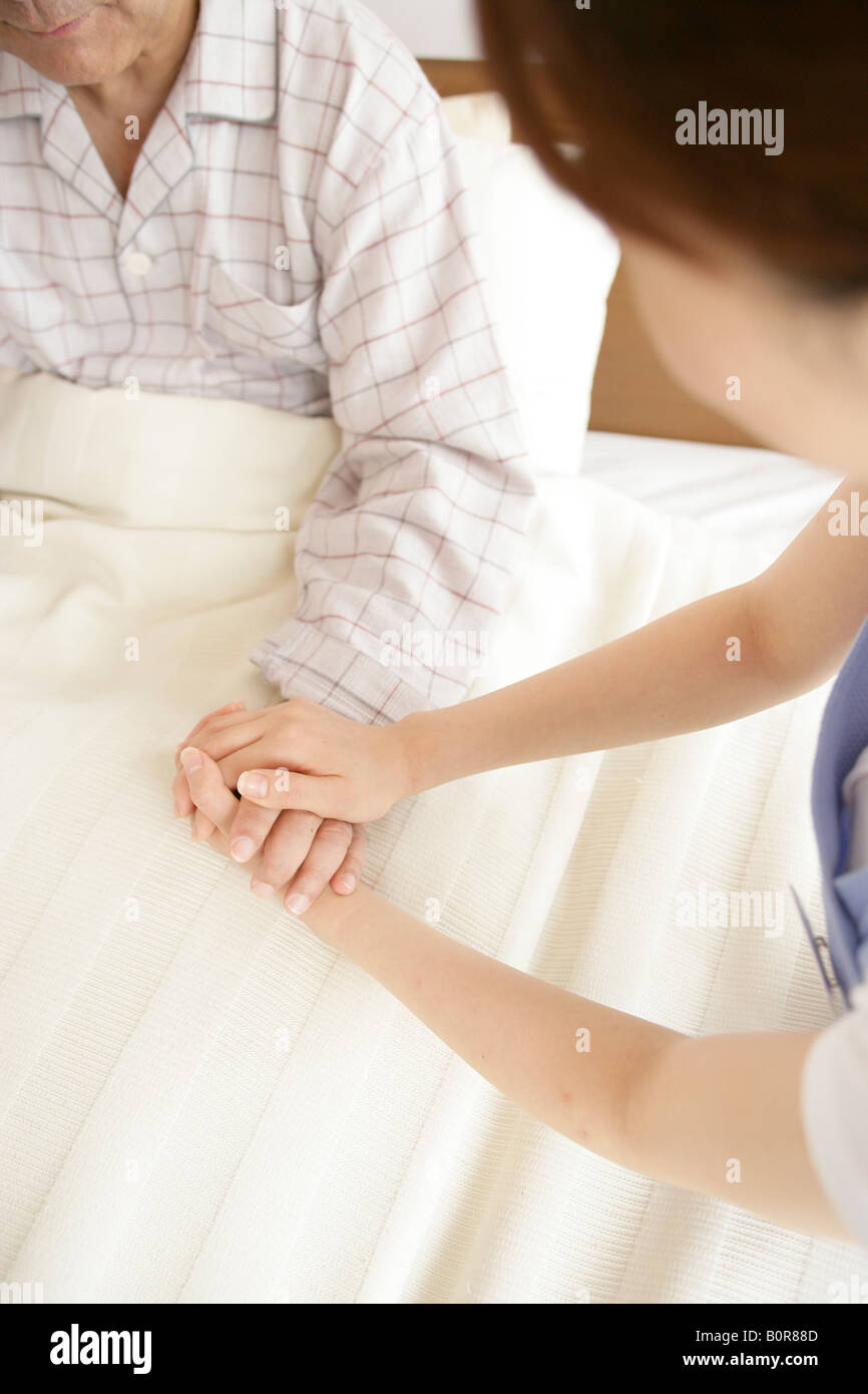 Woman holding patient's hands in nursing home Stock Photo - Alamy