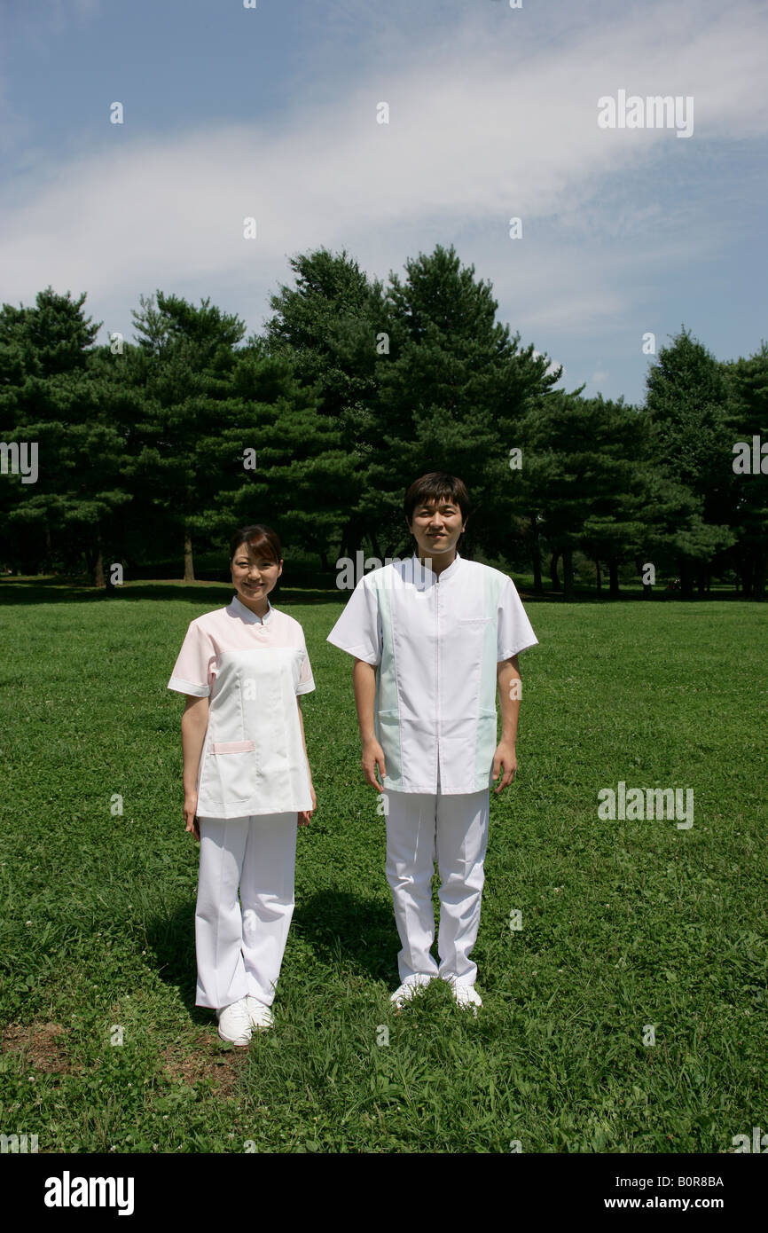Portrait of two nurses standing on grass field in park Stock Photo - Alamy
