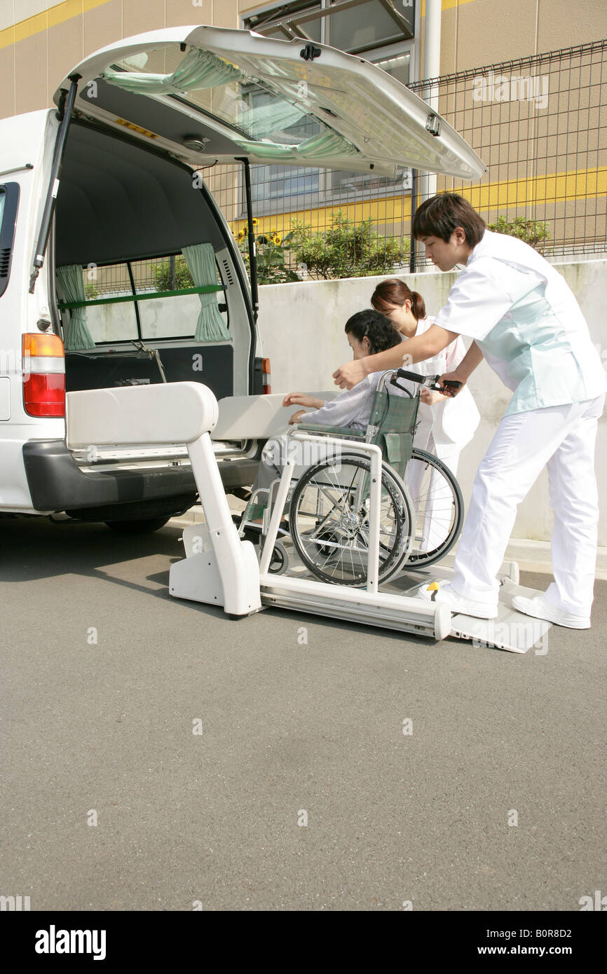 Two nurses helping senior woman on wheelchair getting into car Stock ...