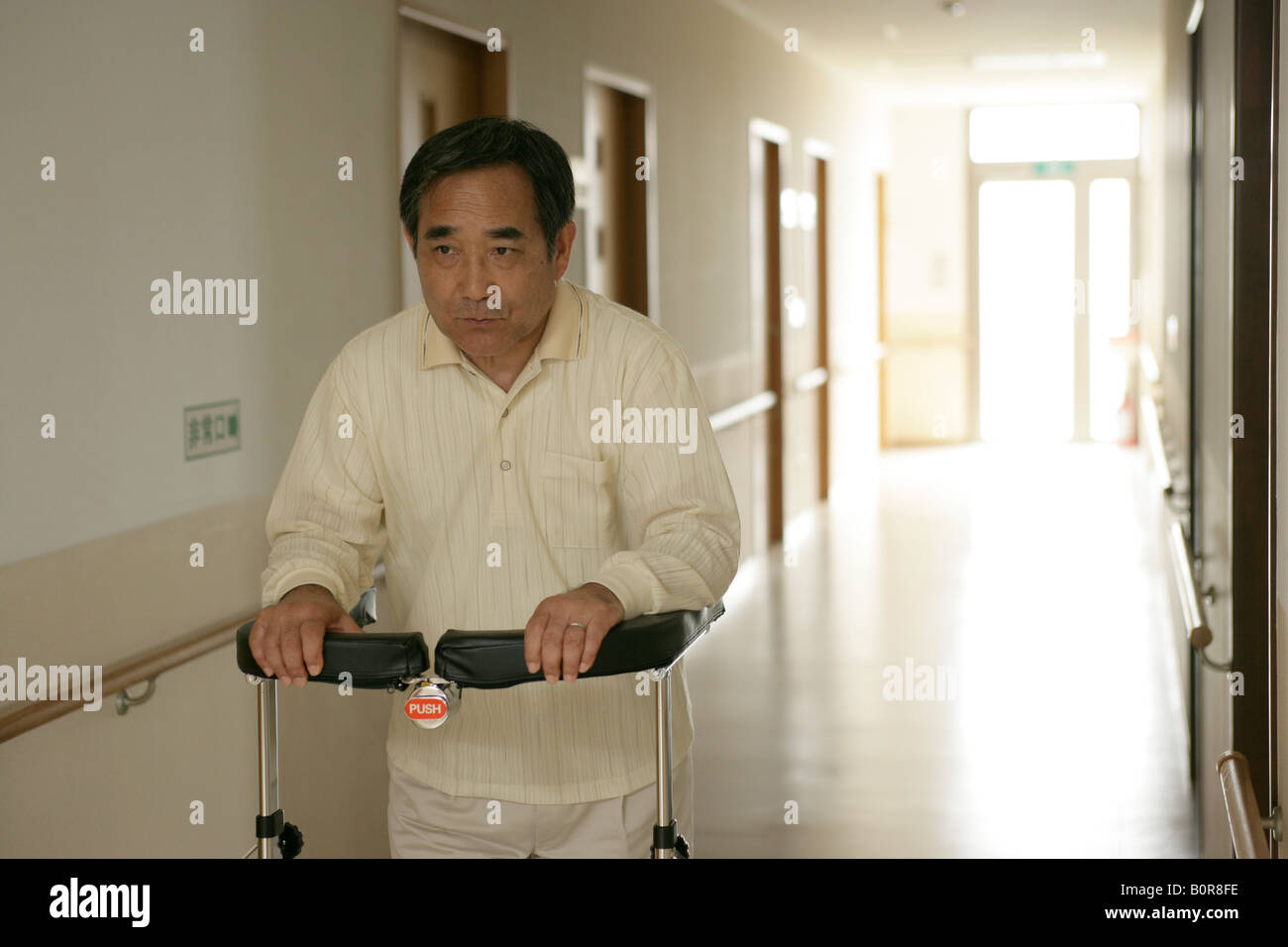 Senior man using walker in corridor Stock Photo - Alamy