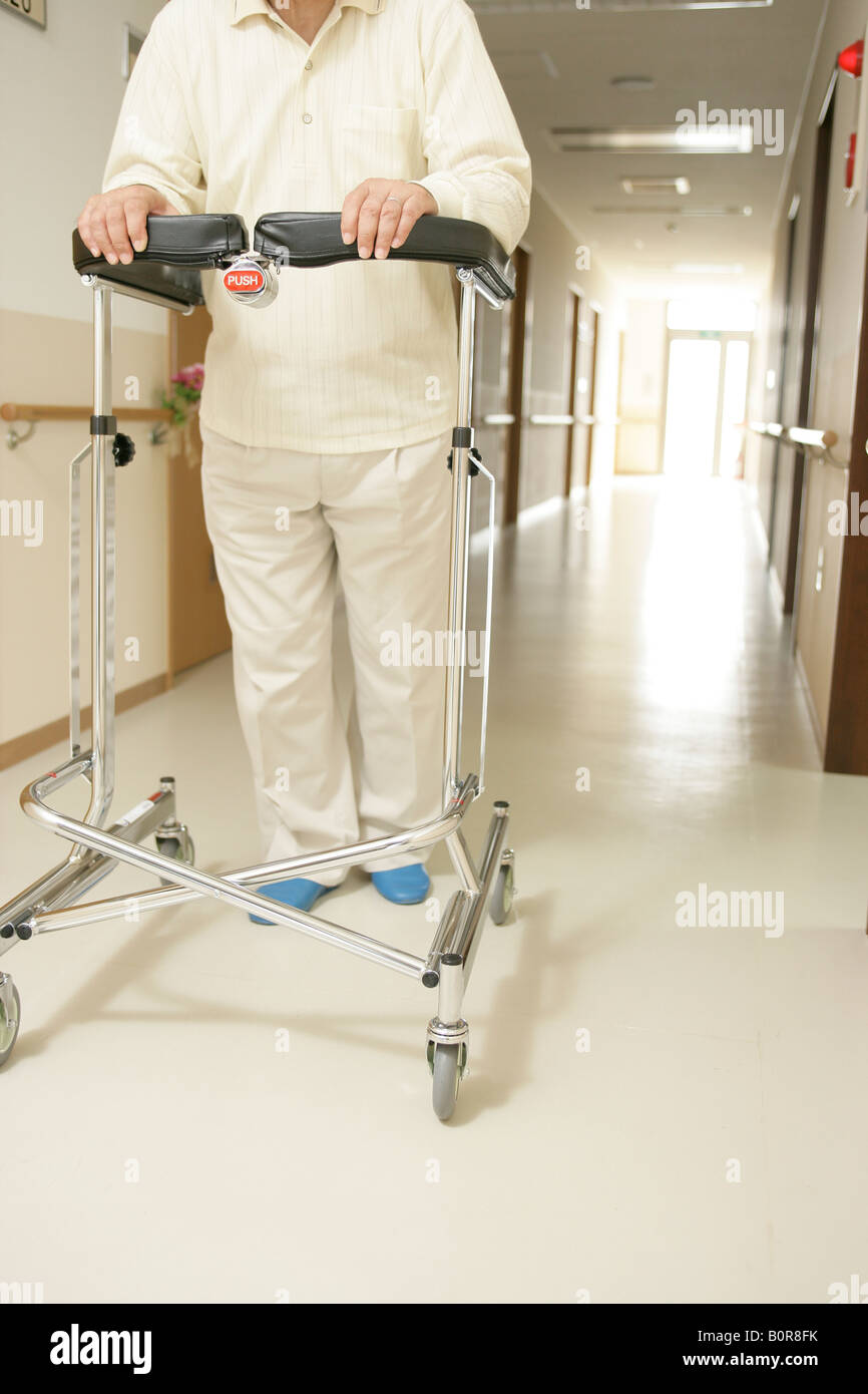 Senior man using walker in corridor Stock Photo - Alamy
