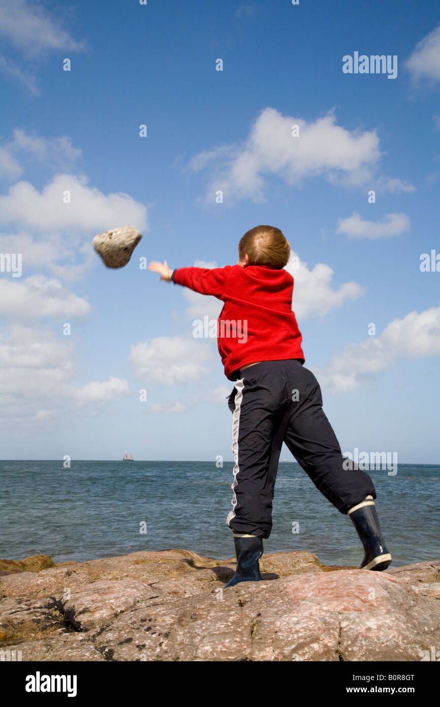 boy throwing heavy rock into sea Stock Photo - Alamy