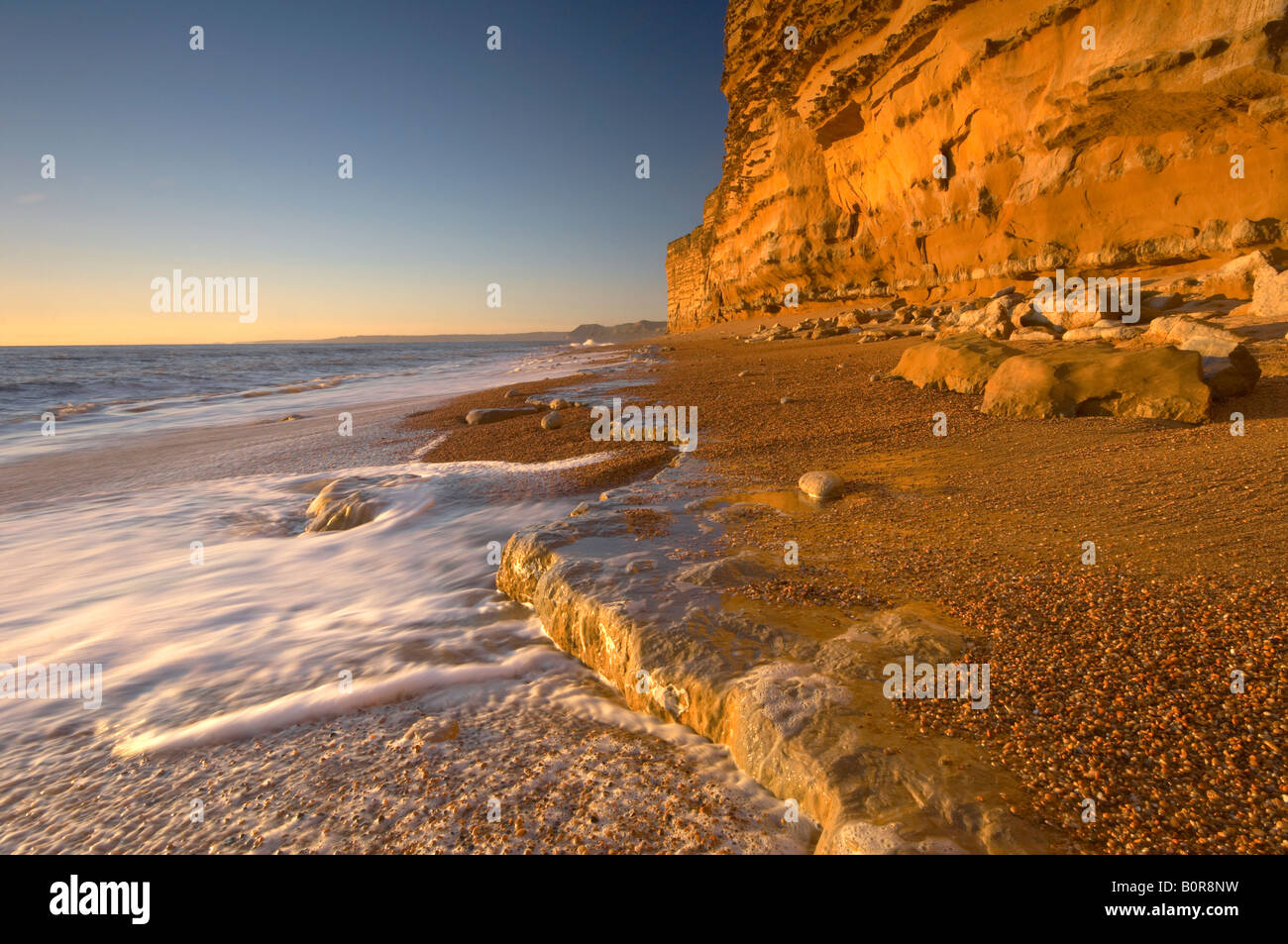 Waves rushing in over the beach and jurassic rock shelf at Burton ...