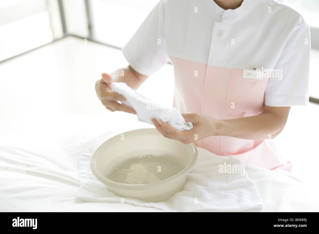Feale nurse with bowl of water at patient's bed, mid section Stock ...