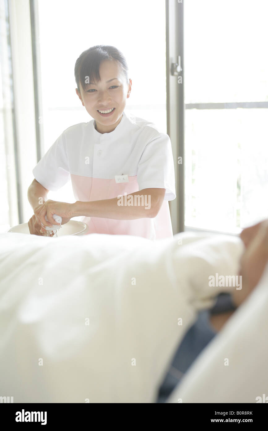 Female nurse with bowl of water at patient's bed Stock Photo - Alamy