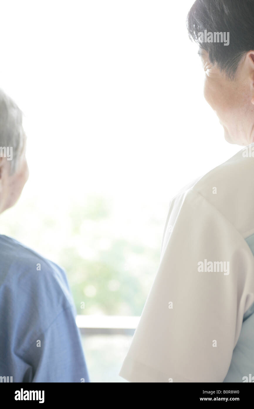 Male nurse and senior man facing window, rear view Stock Photo - Alamy