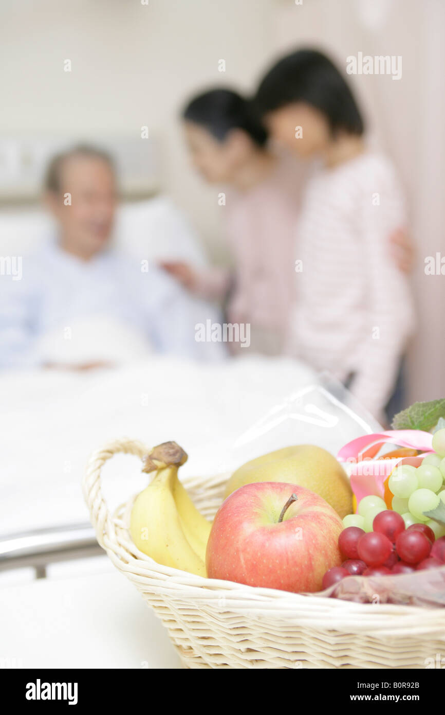Senior woman and granddaughter visiting man in hospital, fruits in ...