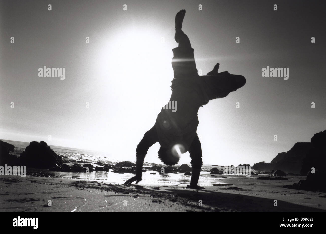 silhouette of man doing cartwheel on beach shore on sand black and ...