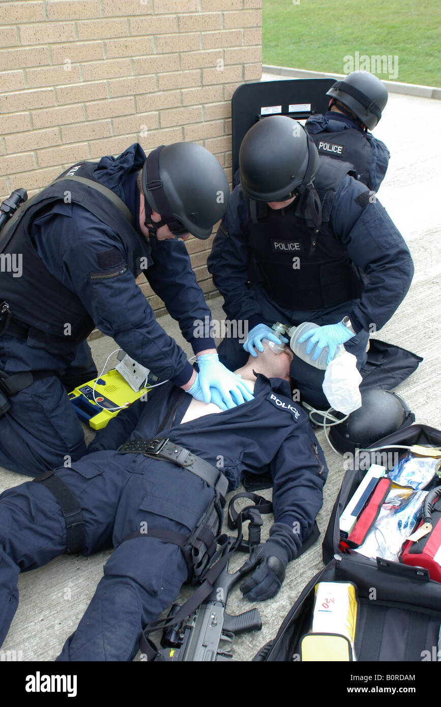 Police firearms officers giving medical assistance to injured officer ...