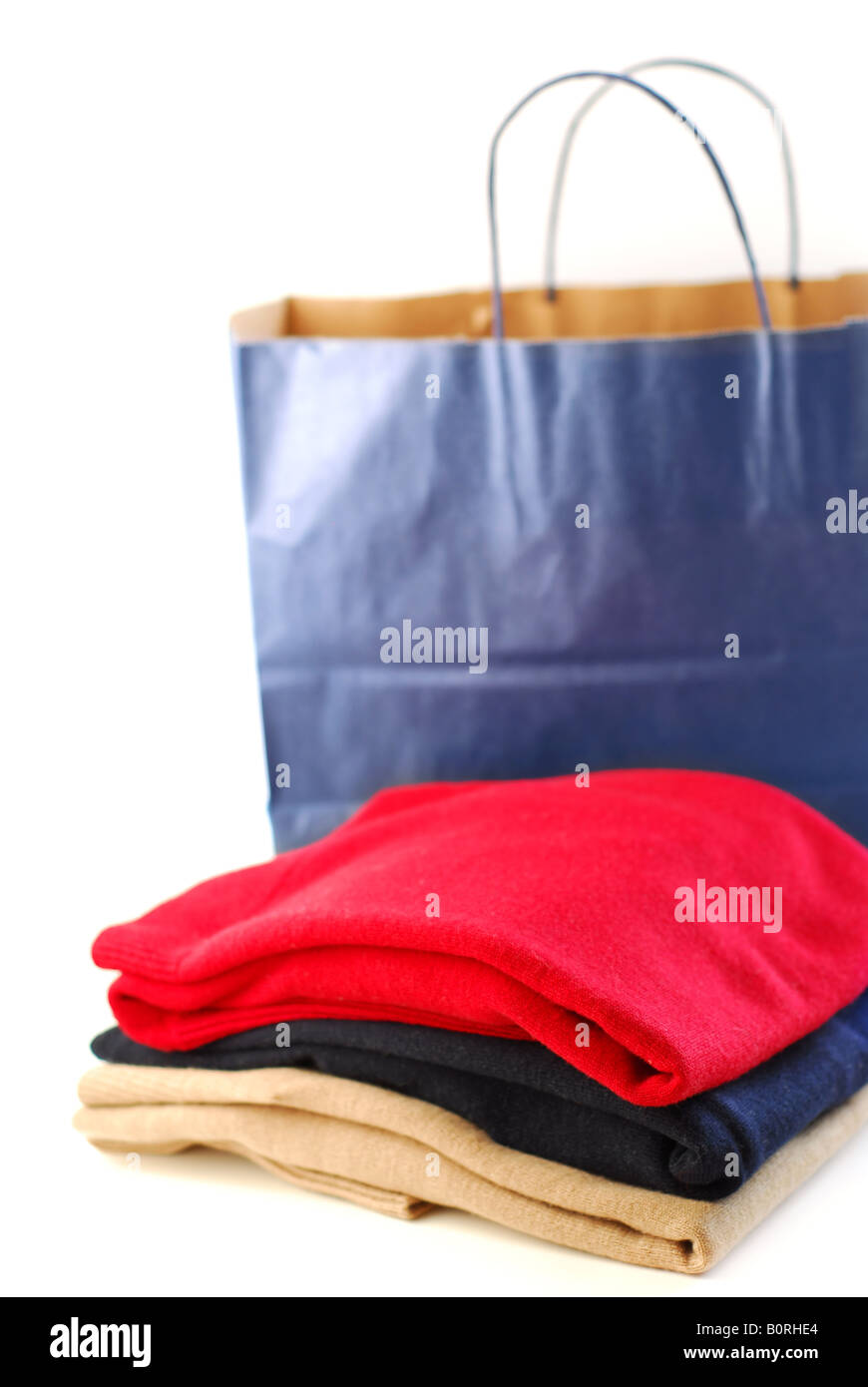 Folded sweaters with a paper shopping bag on white background Stock ...