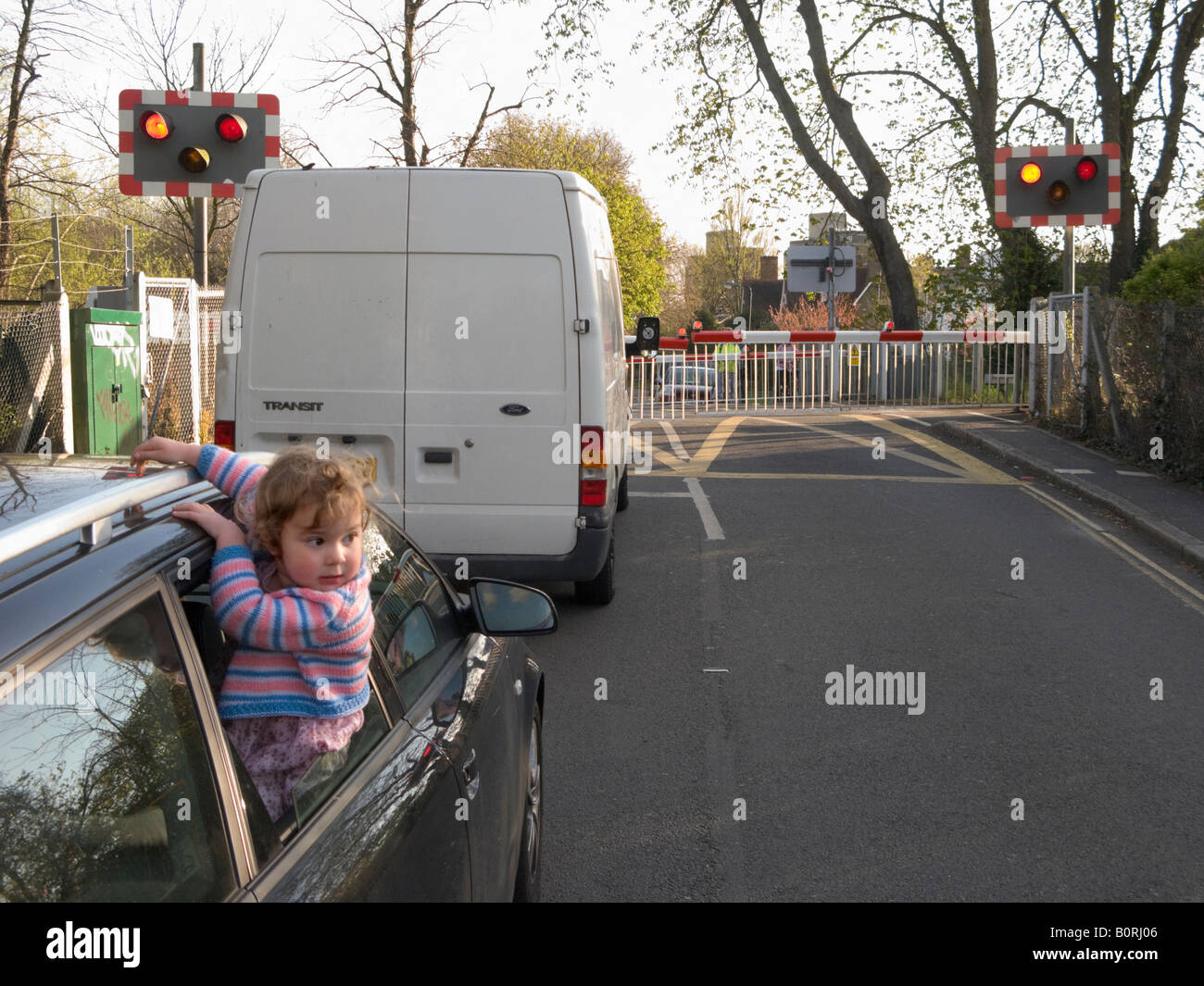Vehicles wait at railway level crossing barrier for train to pass ...