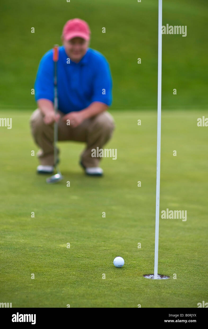 A golfer putting into a hole on a putting green Stock Photo - Alamy