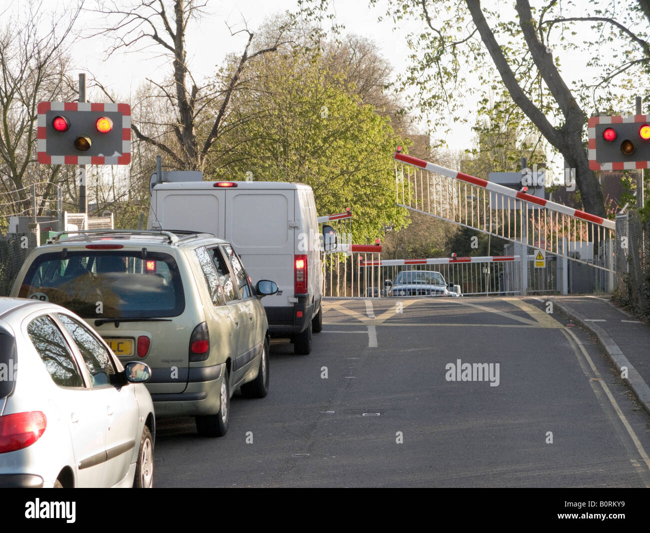 Railway level crossing barrier arms being lowered to halt the traffic ...