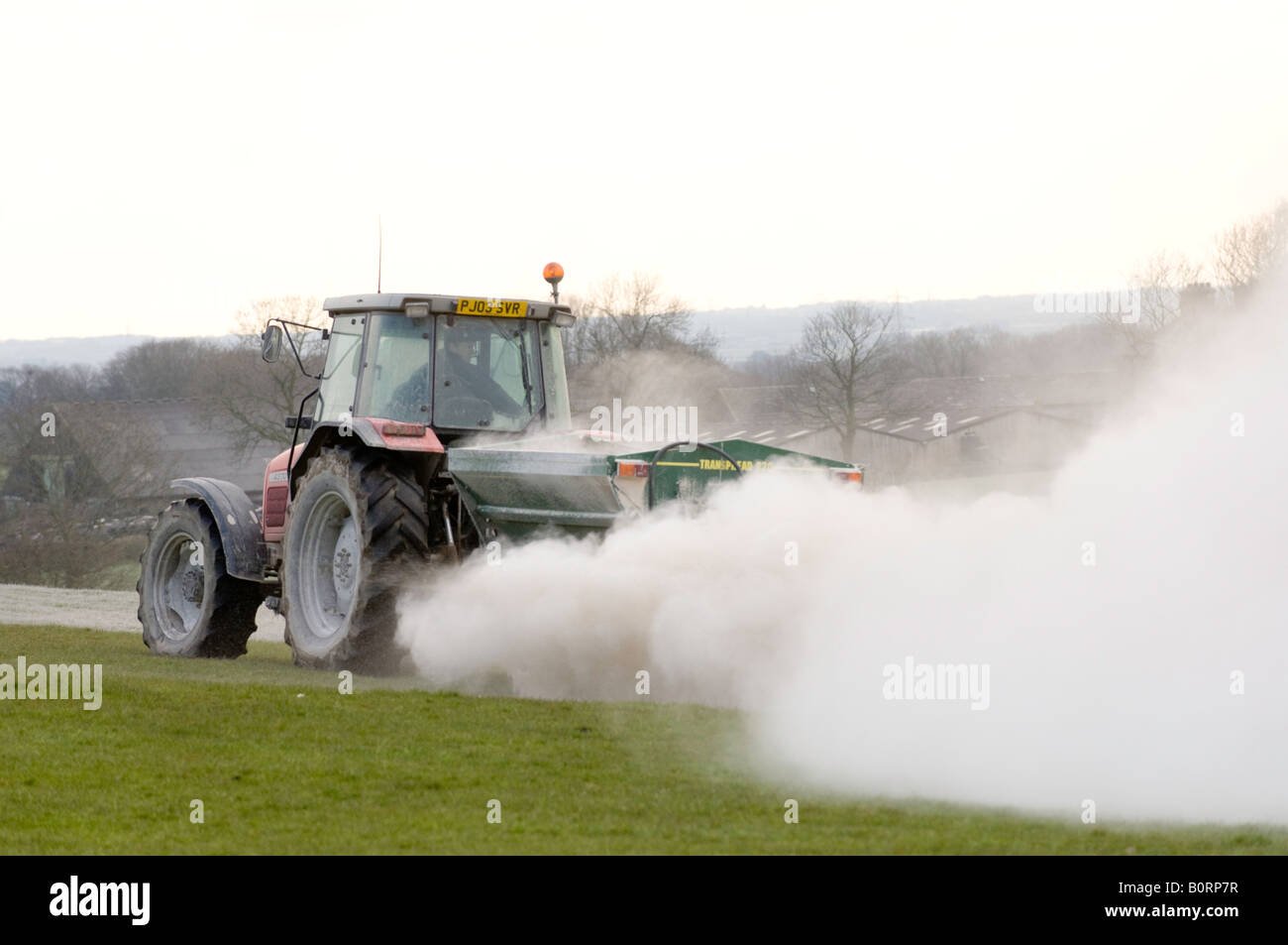 Massey Ferguson tractor pulling a lime spreader which is spreading ...