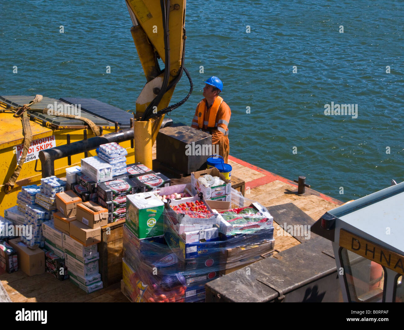 Worker loading cargo onto a boat on the River Dart at Dartmouth Devon ...