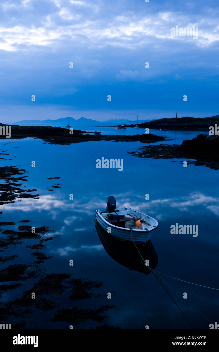 A moored boat rests peacefully on calm, reflective waters on a dusky ...