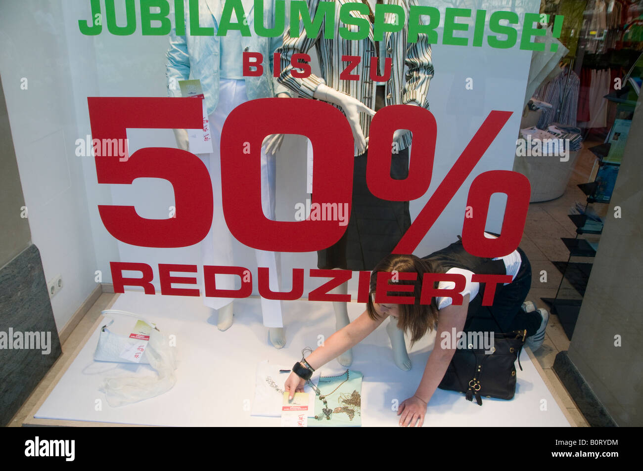 An employee arranges the clothing displayed in a window display of a ...