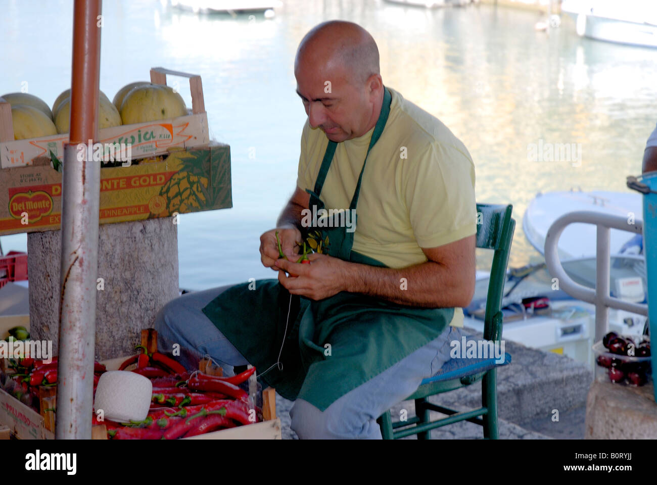 Stringing peppers on market in Sirmione on Lake Garda in Northern Italy ...