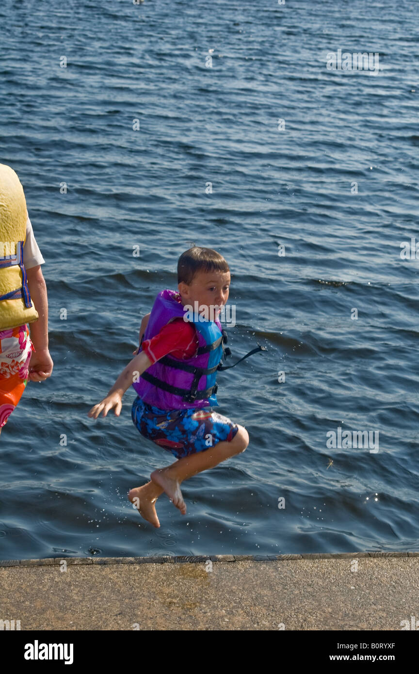 young boy leaps from waterfront dock into summer camp hotel lake Stock ...