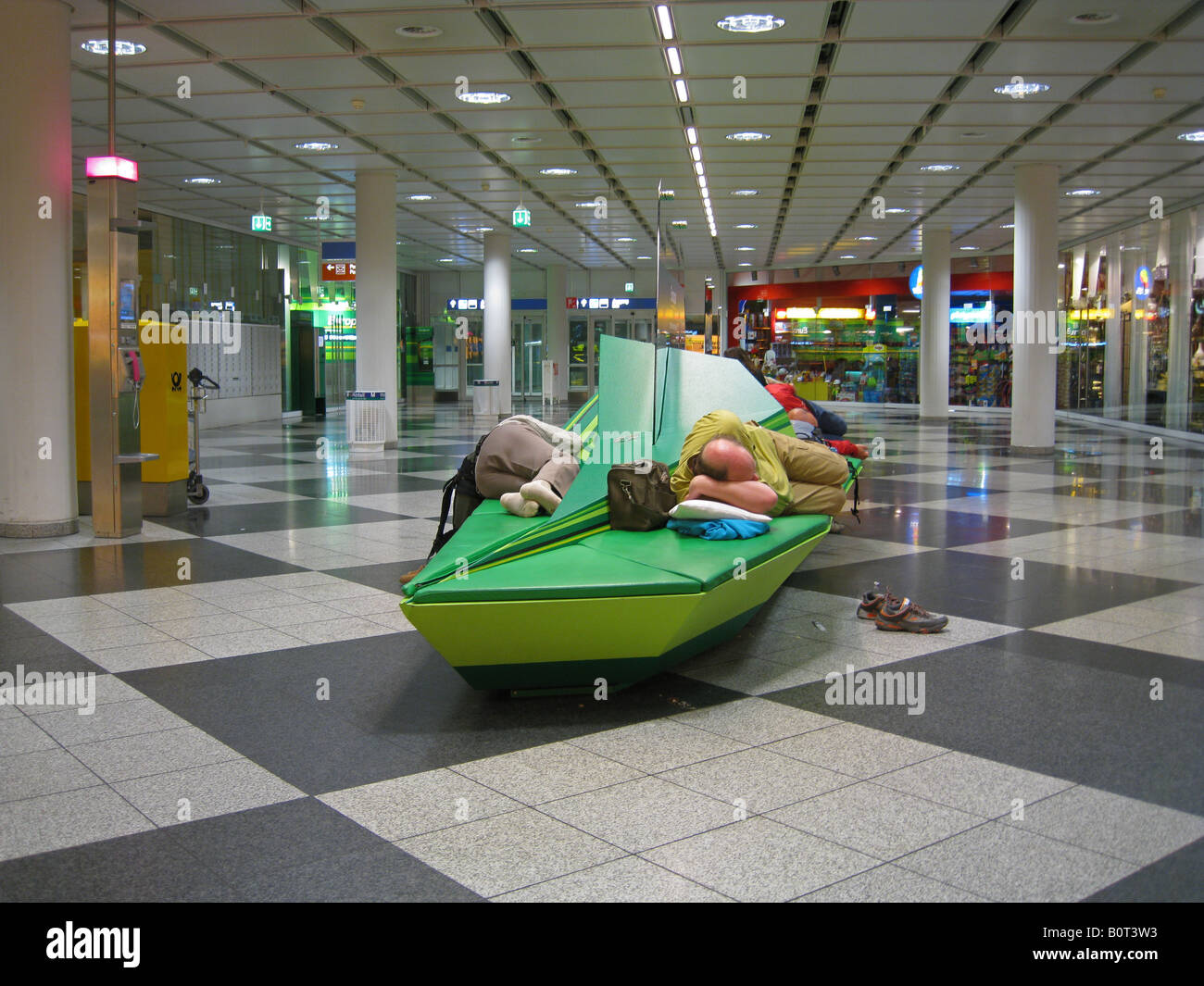 Passengers sleep on benches as they wait for their flight in Munich ...