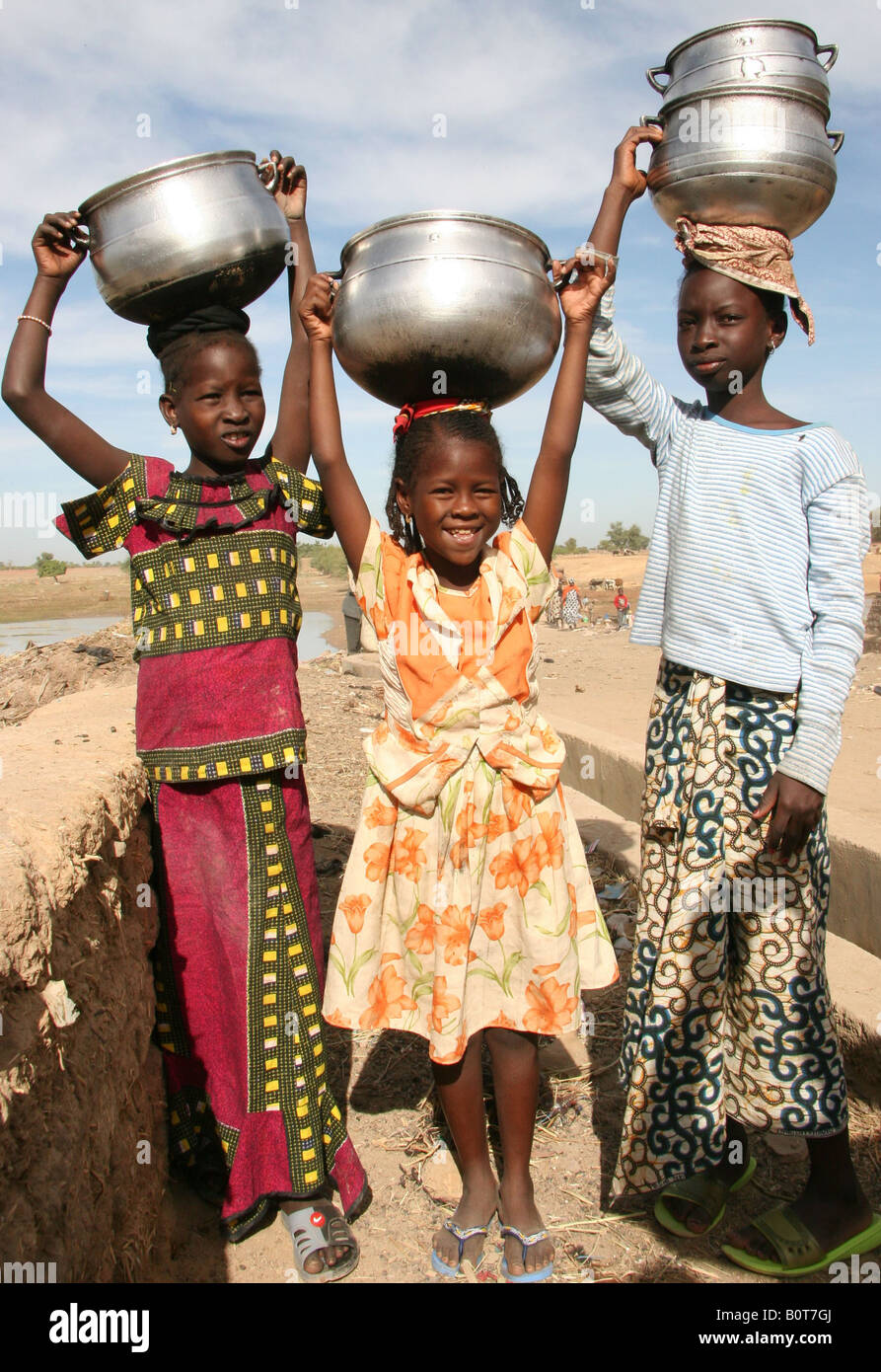 Peul girls carrying milk Stock Photo - Alamy