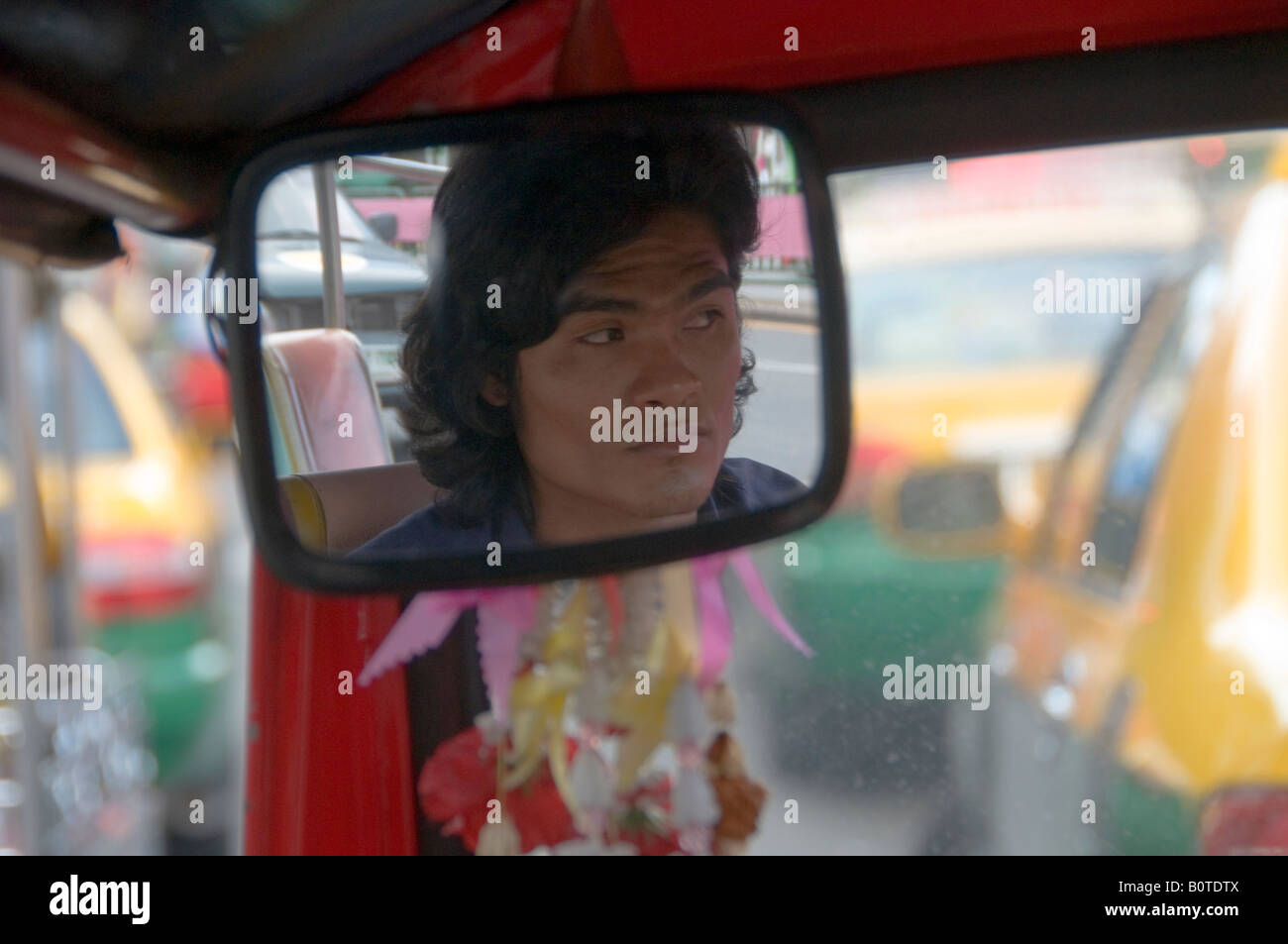 A driver is reflected in the rearview mirror of an Auto rickshaw taxi ...