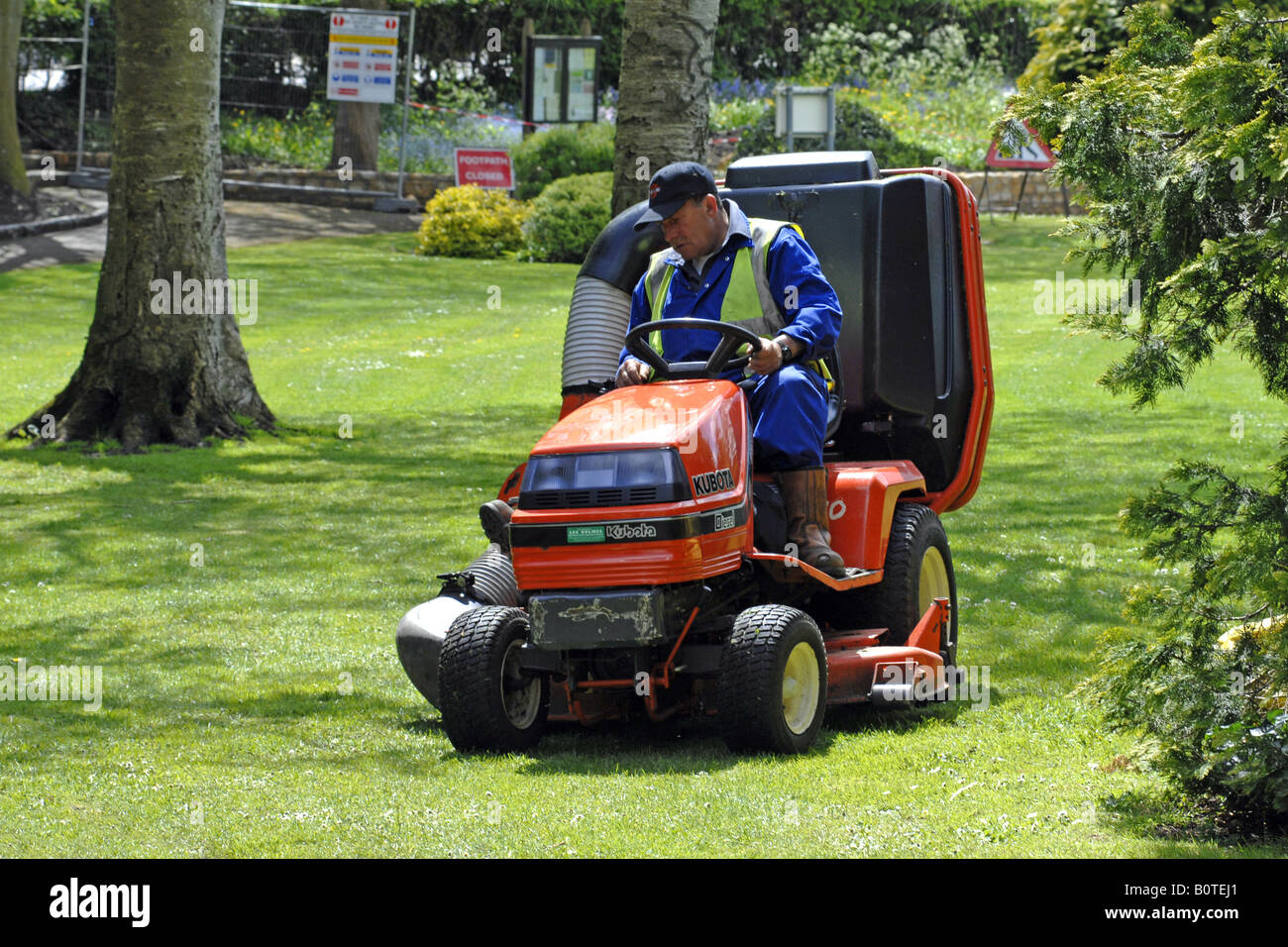 A male worker using a ride on lawn mower in a park Stock Photo - Alamy
