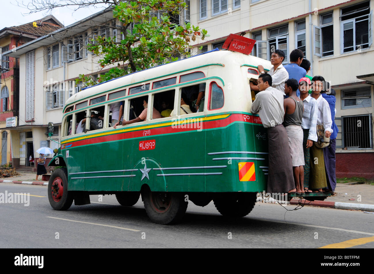 People hanging out of from a packed bus in downtown Yangon, Myanmar ...