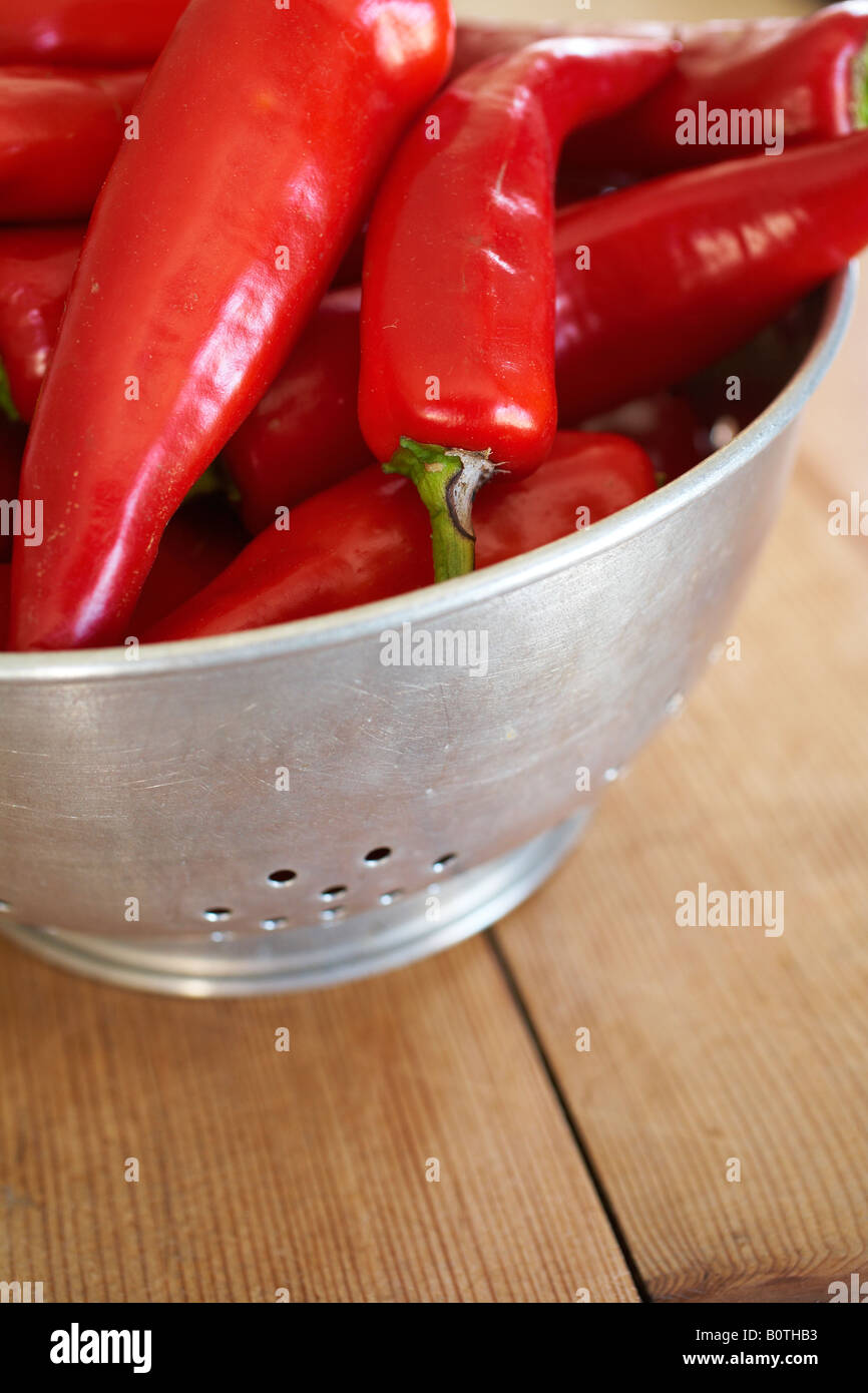 sweet red chilli peppers in colander on table Stock Photo - Alamy