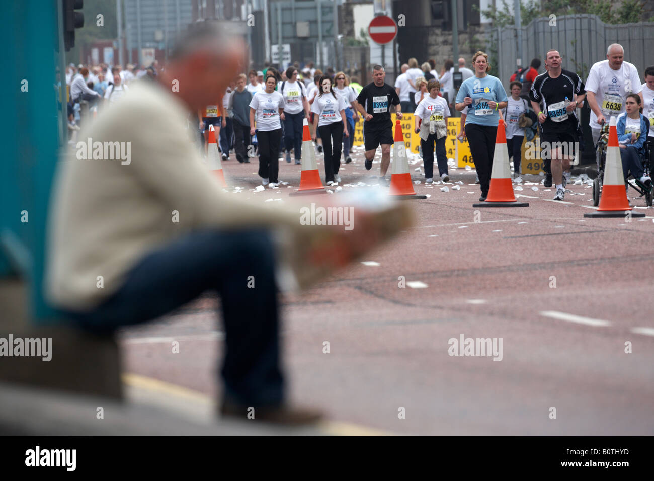 man sitting reading the paper as competitors run past during the ...