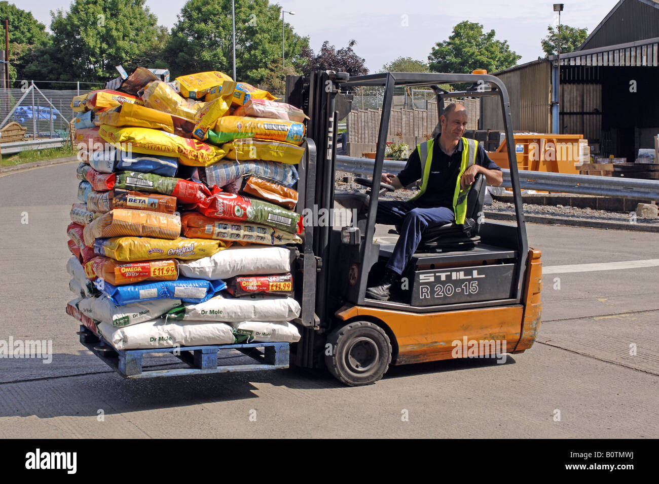 A man using a forklift truck to move bags of gardening compost at a ...