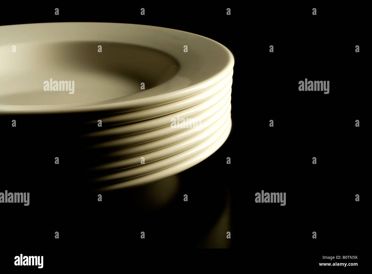 Plates against black background Stock Photo - Alamy