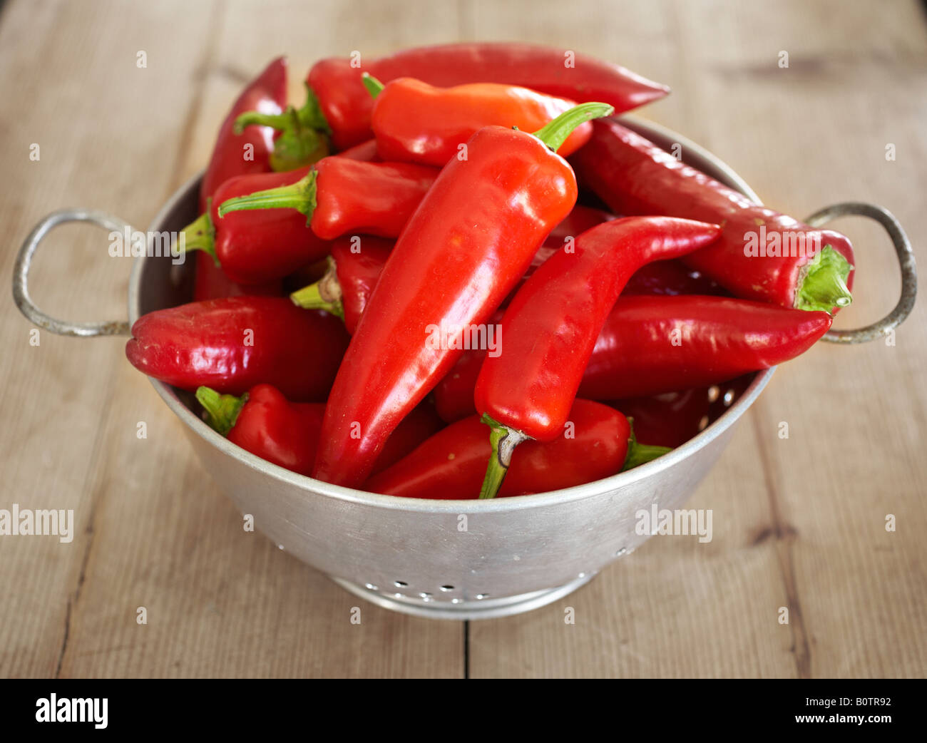 sweet red chilli peppers in colander on table Stock Photo - Alamy