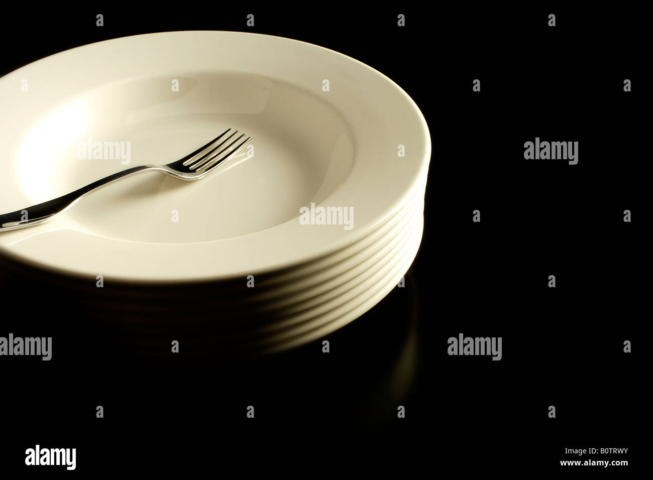 Plates with fork against black background Stock Photo - Alamy