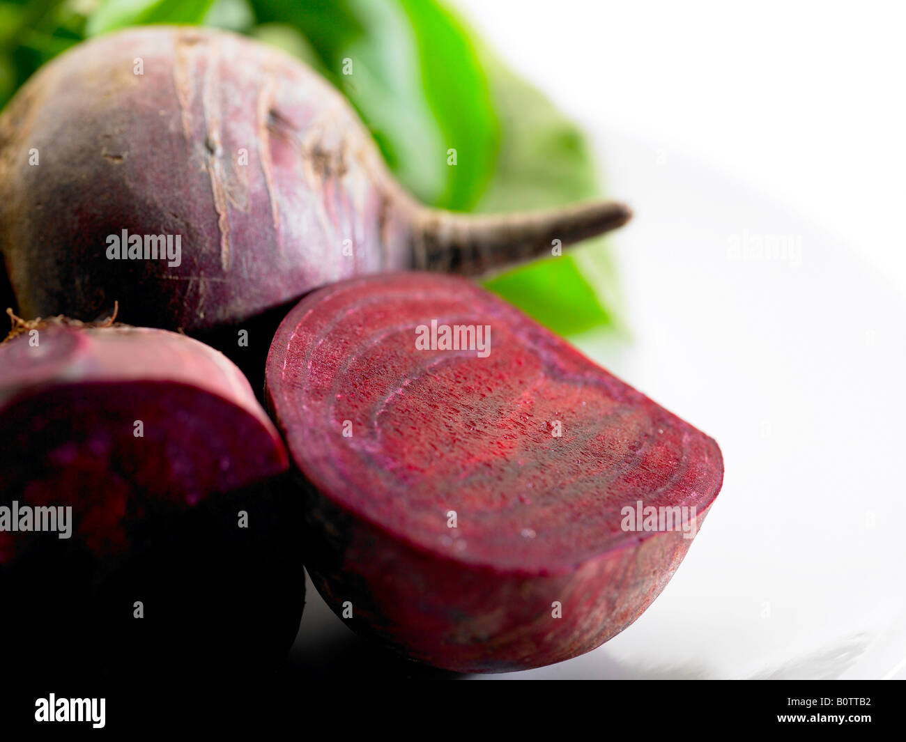 cut bright red beetroot and leaves against white background Stock Photo ...