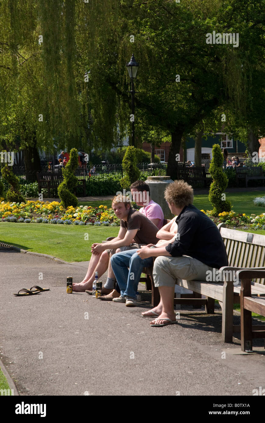 group of male youths on a park bench drinking in the sun Stock Photo ...