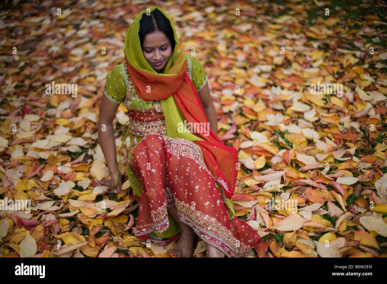 Pakistani woman 30s wears traditional clothing in a garden with autumn ...