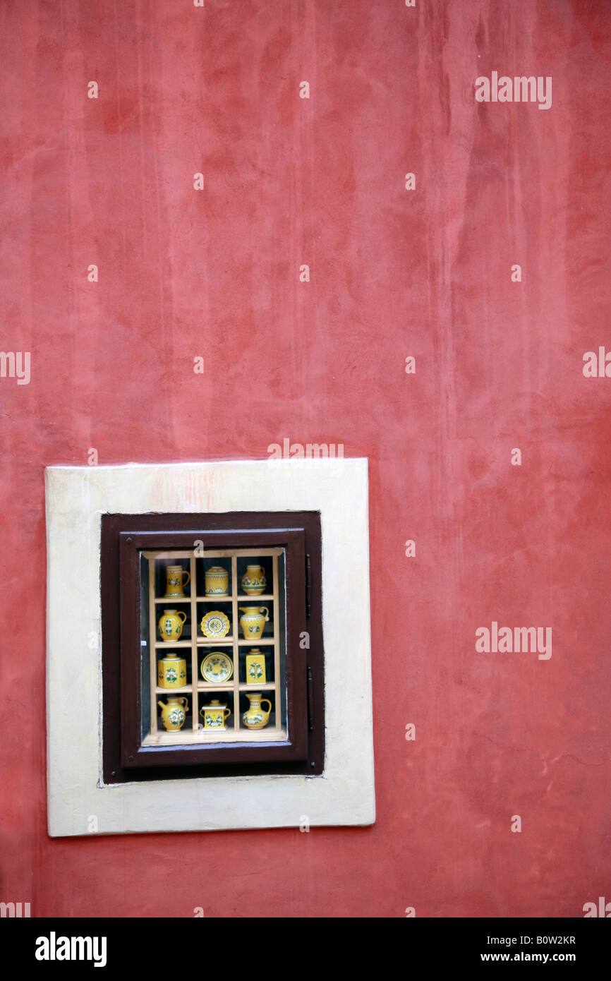 Small window in a red painted wall. Yellow ceramics on display Stock ...