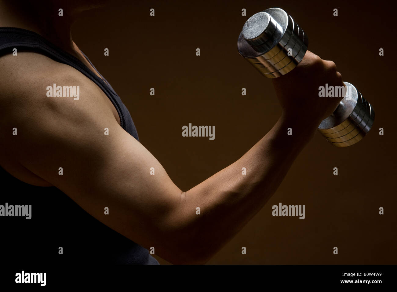 Muscular man holding dumbbell, midsection Stock Photo - Alamy