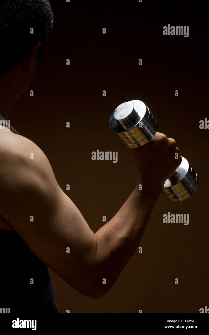 Muscular man holding dumbbell, midsection Stock Photo - Alamy