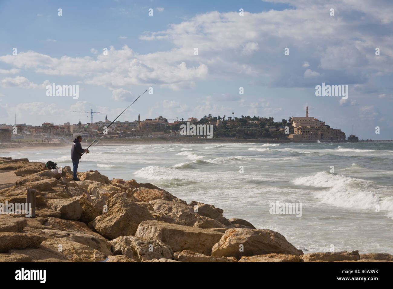 Fisherman fishing on the Tel Aviv shoreline, view toward Jaffa, Israel ...