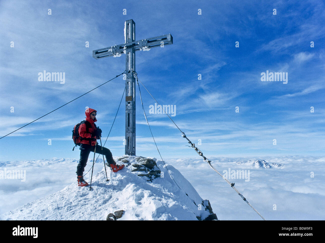 Mountain climber standing on the peak of Mt. Similaun next to an iron ...