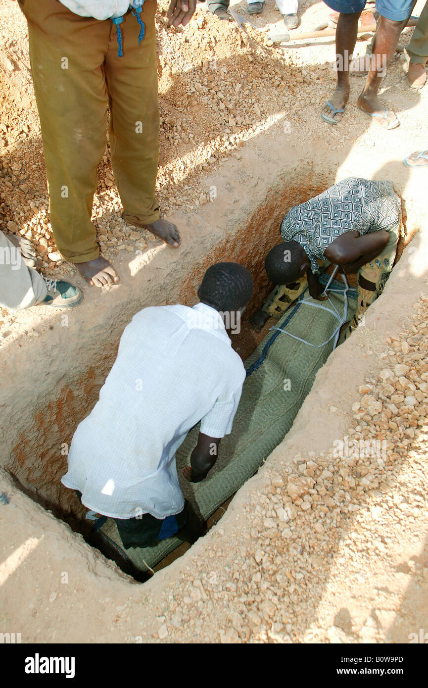 Body of a woman who died of HIV/AIDS being lowered into a grave during ...