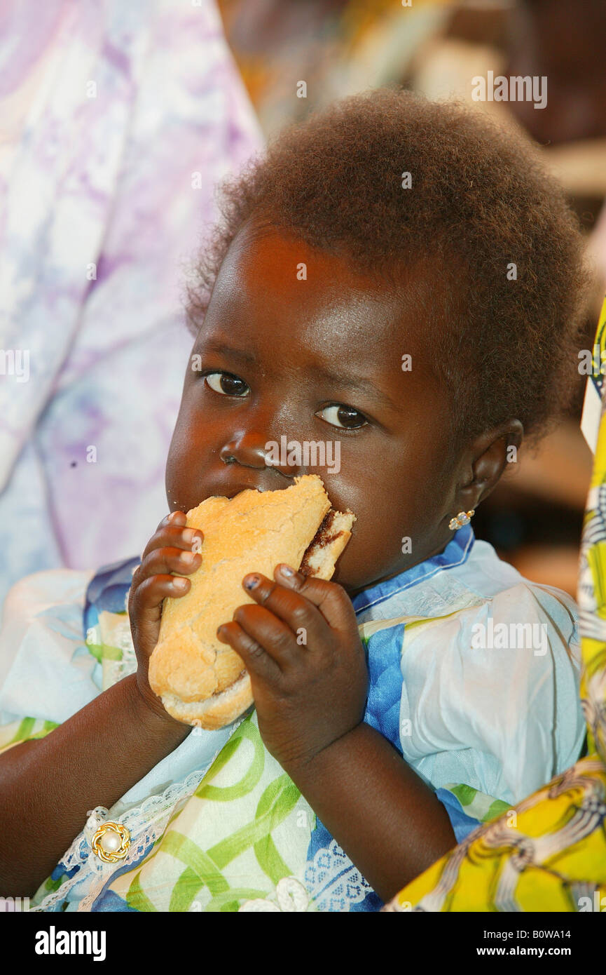 Small child eating bread, communal meal after a church service, Garoua ...