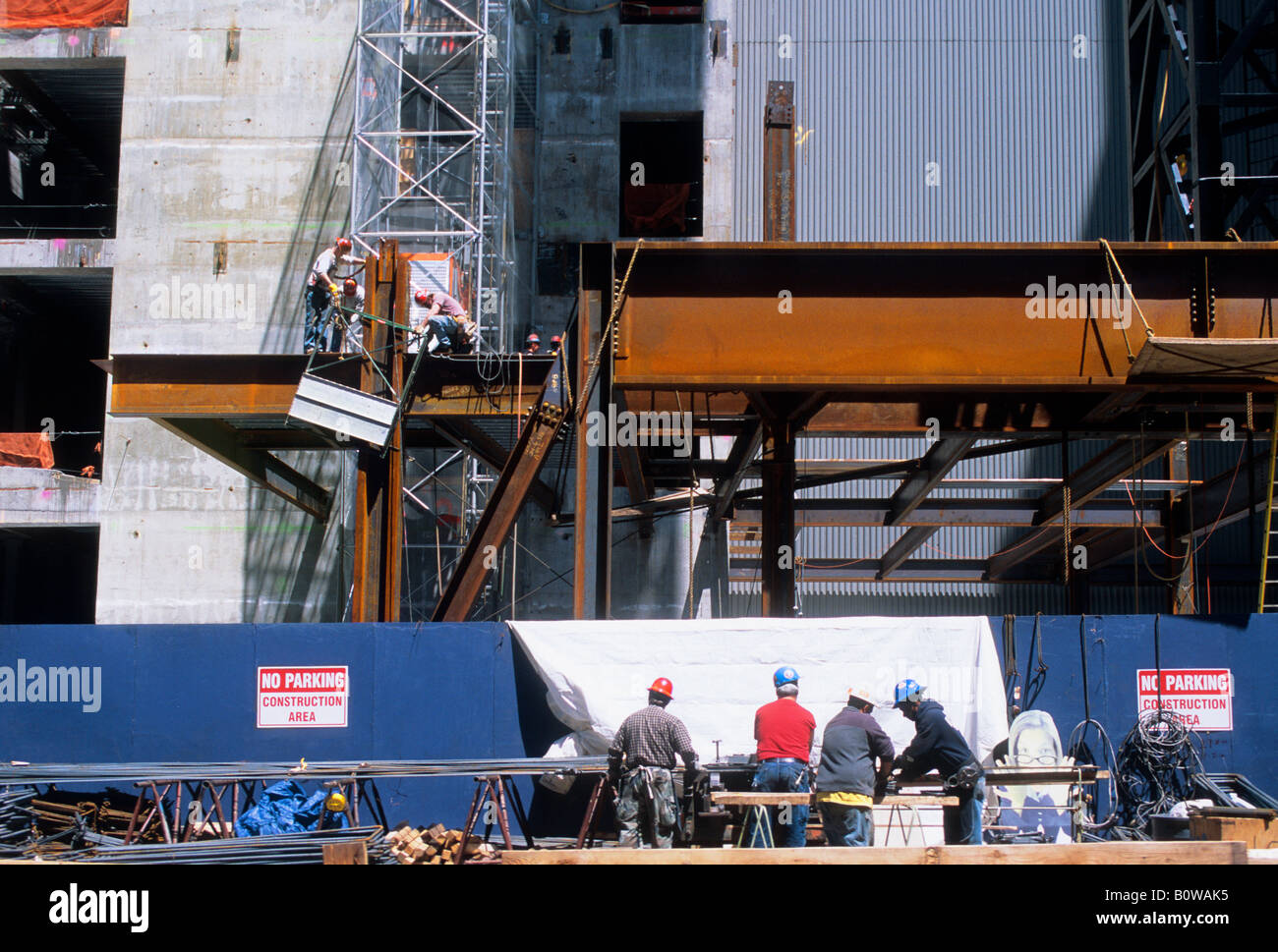 Construction site area and hard hats working hoisting steel plank ...