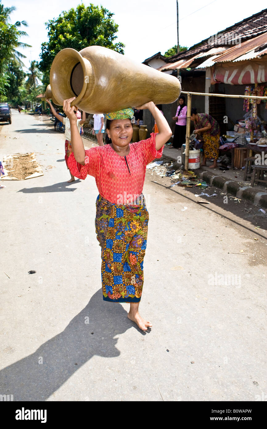 Woman carrying a traditionally crafted jar on her head, Banyumulek ...
