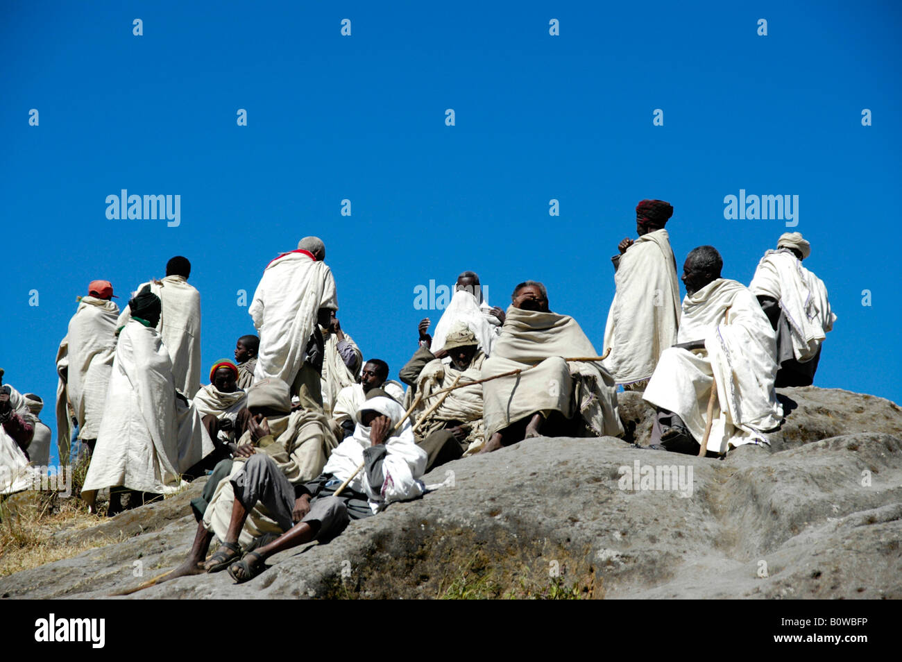 Ethiopian Orthodox followers dressed in white capes gathered on a rock ...